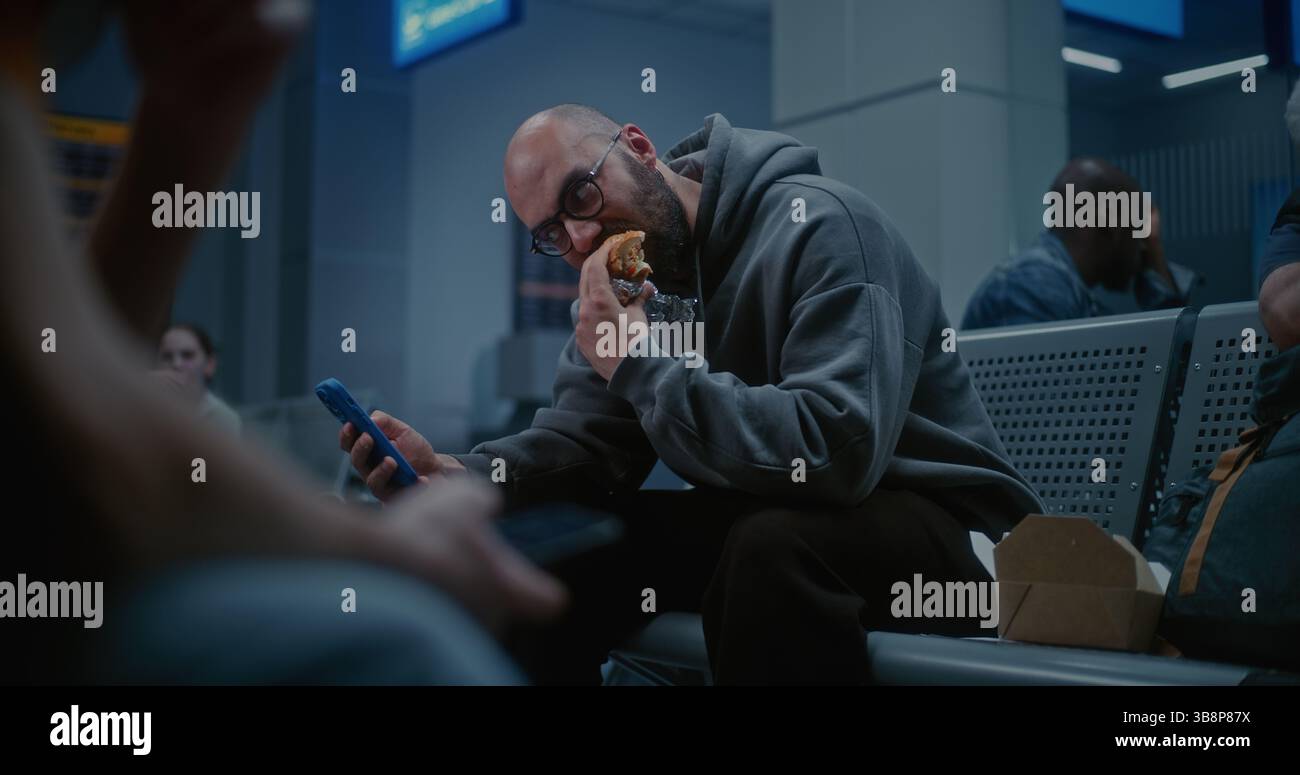 Departure Lounge of Airline Hub at Night: Man Eating Burger and ...