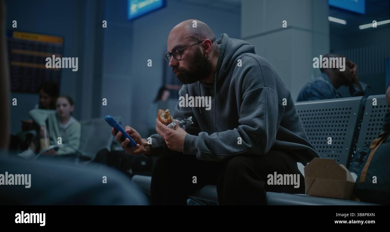Departure Lounge of Airline Hub at Night: Man Eating Burger and ...