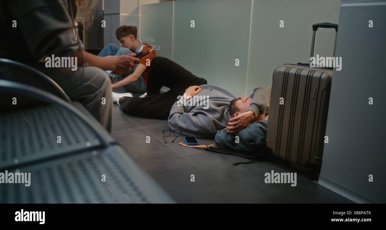 Crowded International Airport Terminal: Tired Man Sleeping on the Floor near Suitcase in ...