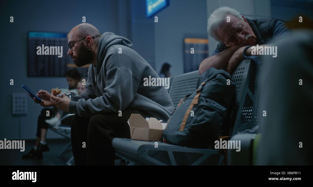 Boarding Lounge of Airline Hub at Night: Man Eating Fast Food and Using ...