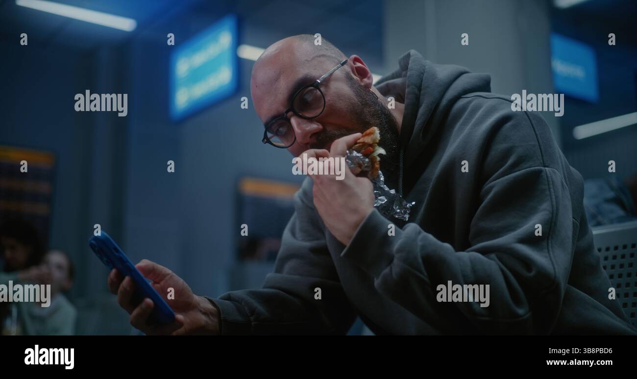 Boarding Lounge of Airline Hub at Night: Man Eating Burger and ...