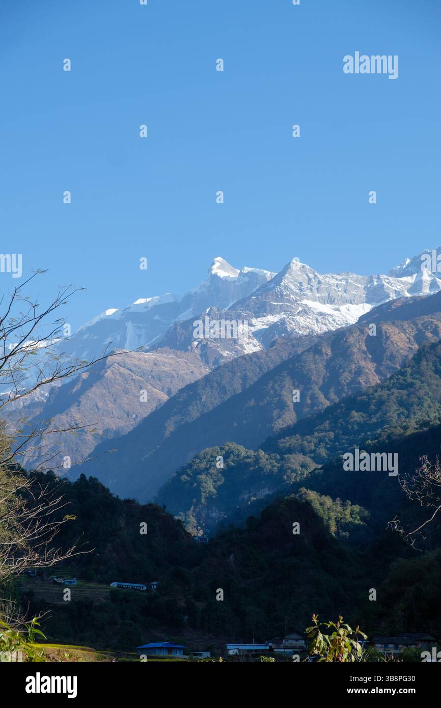 Annapurna South peak towers over a village in Nepal. Trekkers visit to ...