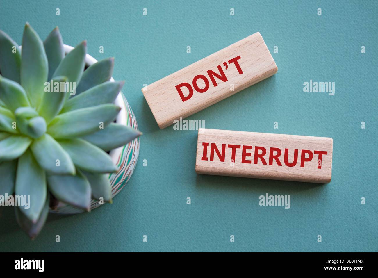 Dont interrupt symbol. Concept word Dont interrupt on wooden blocks. Beautiful grey green ...