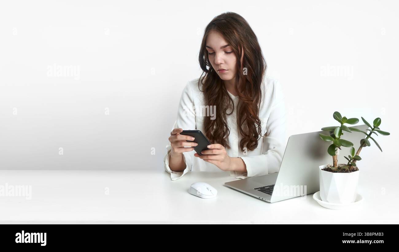 Young woman working remotely with laptop and smartphone in minimalist ...