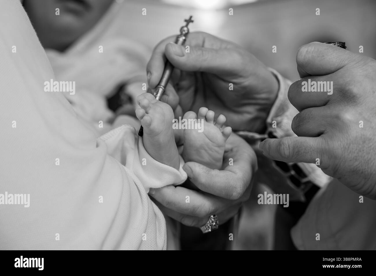 A close-up black and white photograph depicts a solemn baptism ceremony ...