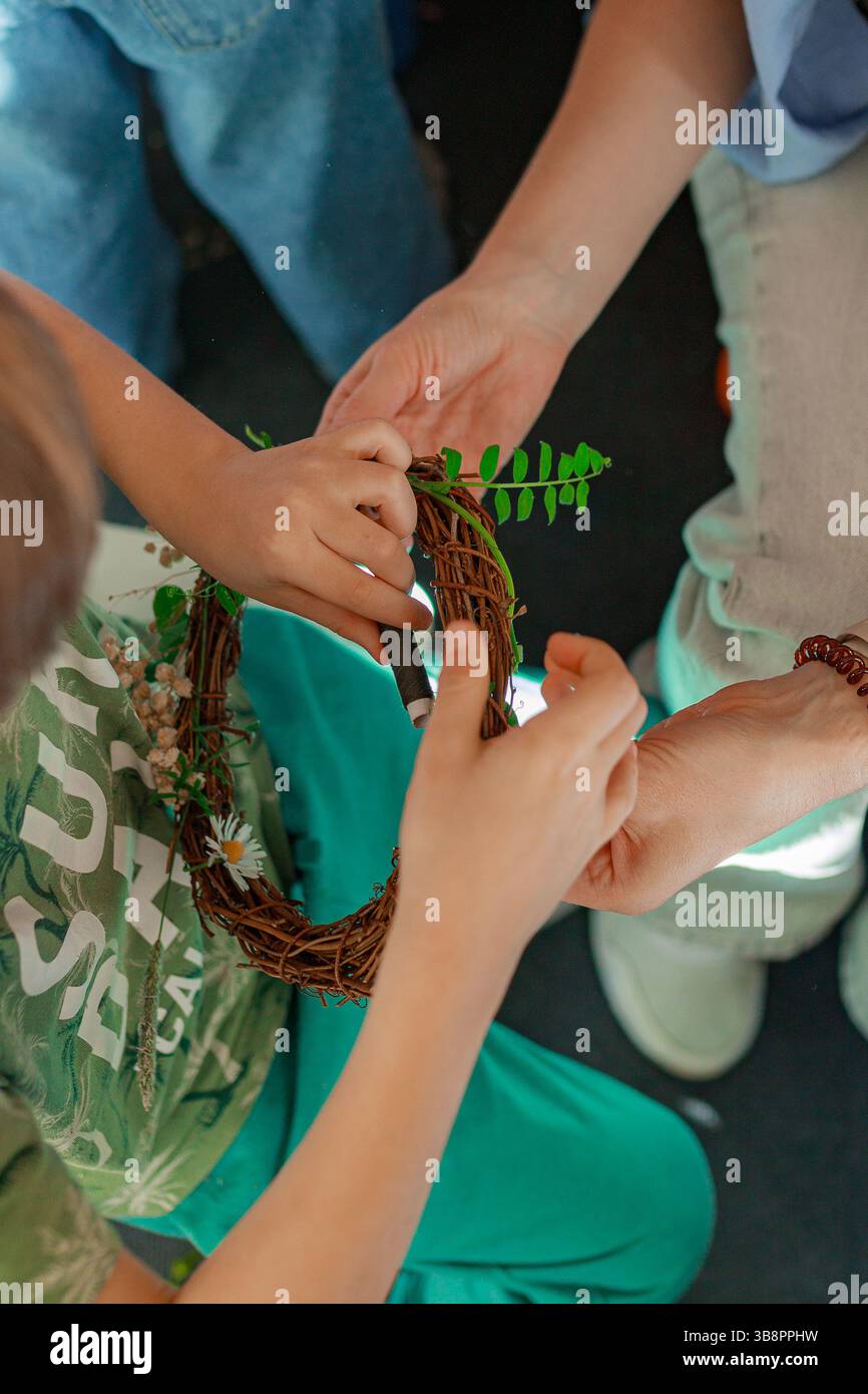 Children making natural wreath with flowers and leaves during outdoor ...