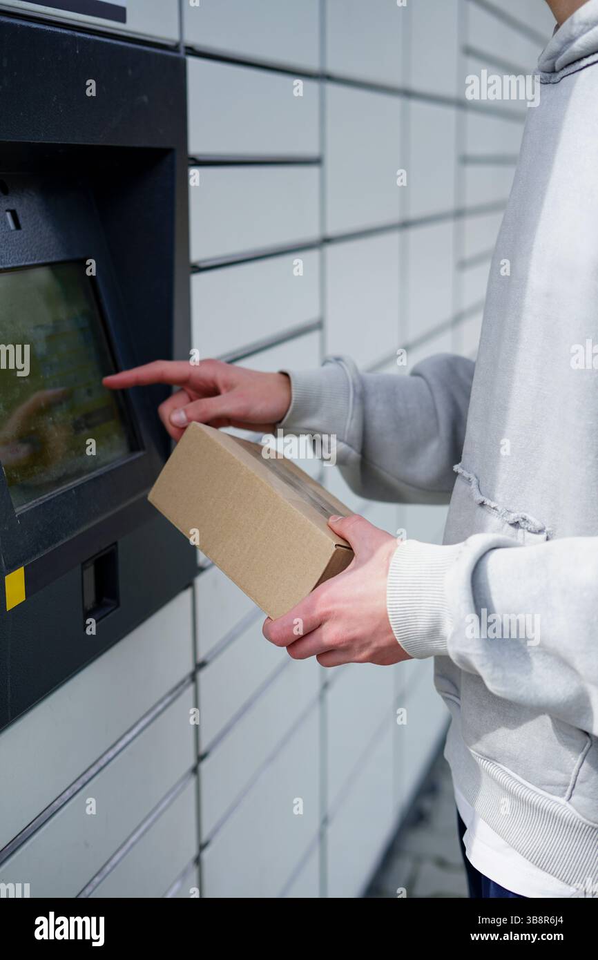 Male in grey hoodie deposits cardboard package using touchscreen ...