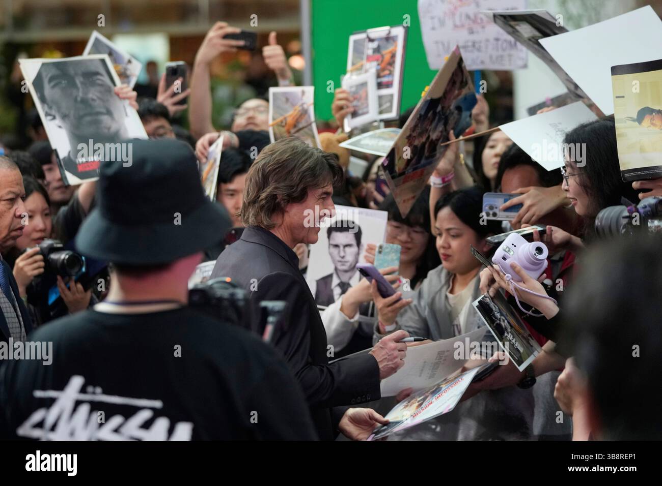 Tom Cruise signs an autograph for fans during a red carpet event to ...