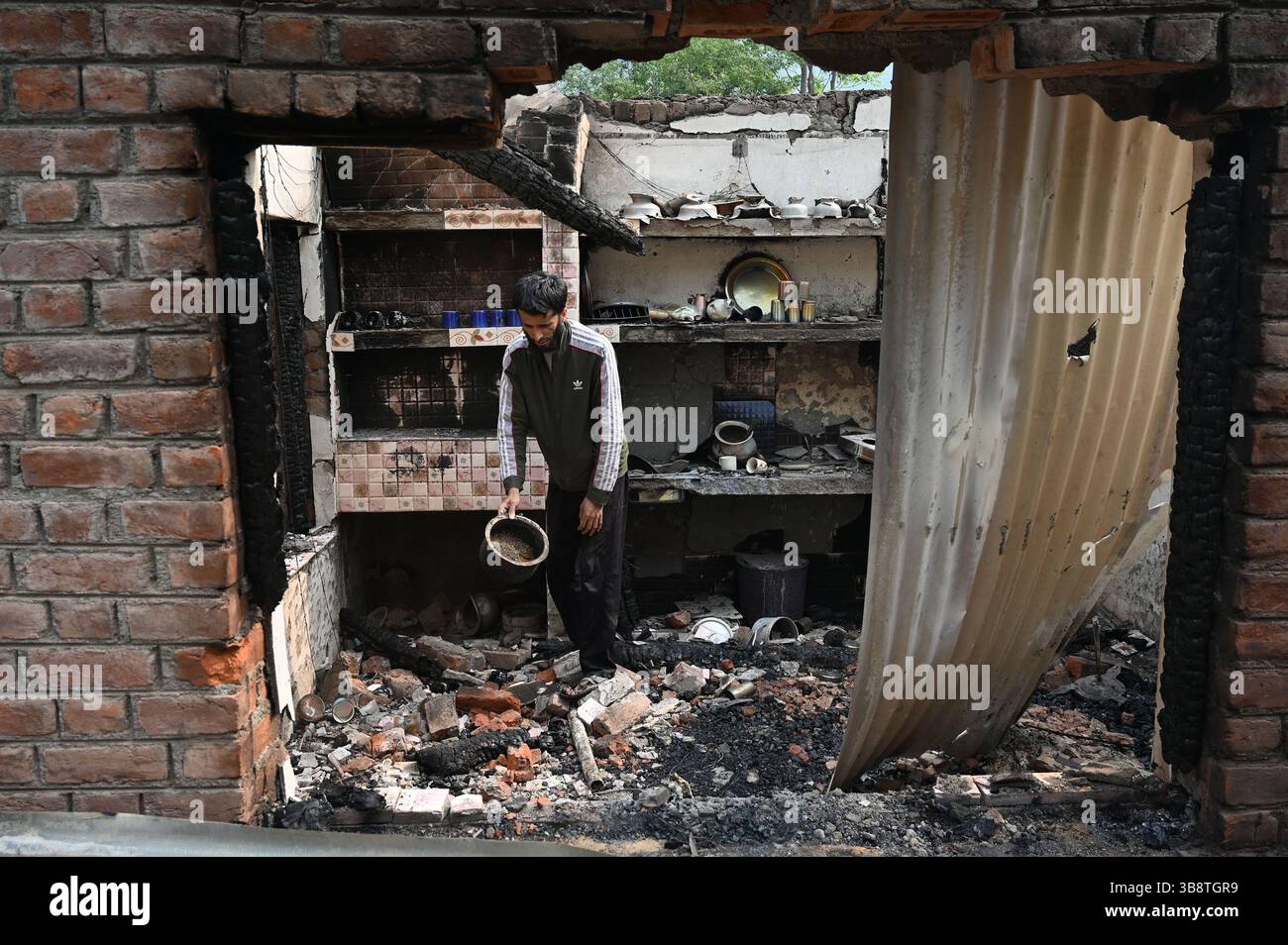 URI, INDIA - MAY 8: A man picks damaged utensils from his house after a ...