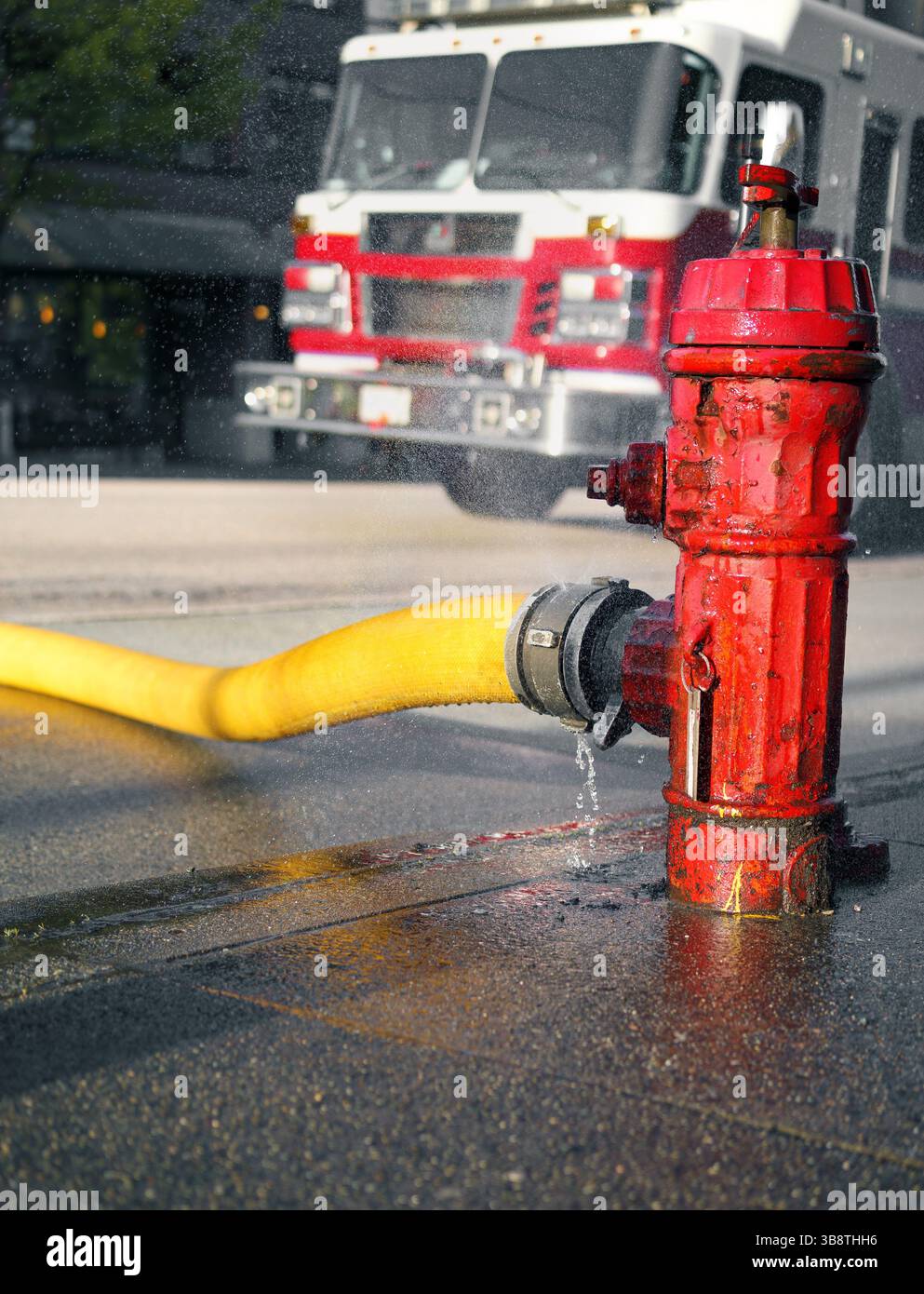 Fire hydrant with hose attached and defocused fire truck. Supply line ...