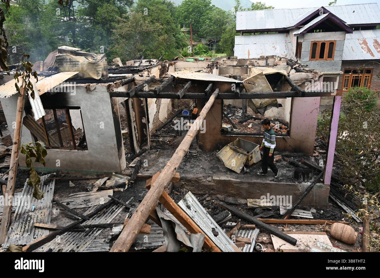 URI, INDIA - MAY 8: People walk outside a damaged houses after a ...