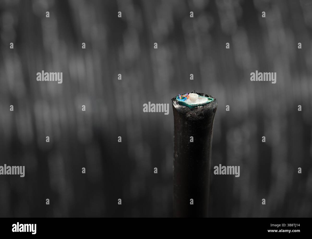 Fiber optic cable in front of defocused black cable reel. Close up of ...