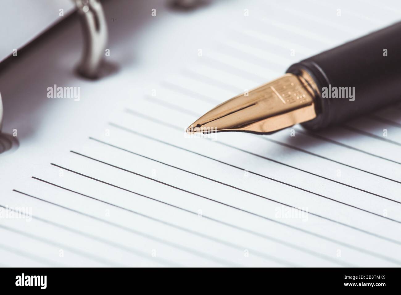 Metal feather pen on the ruled paper in the notebook Stock Photo - Alamy