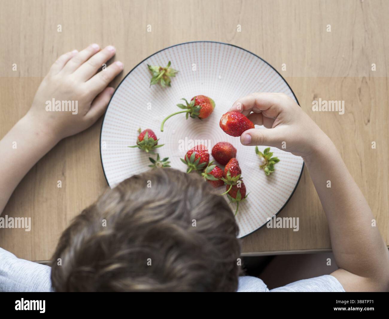 Little unrecognizable boy eats fresh strawberry with relish. Happy ...