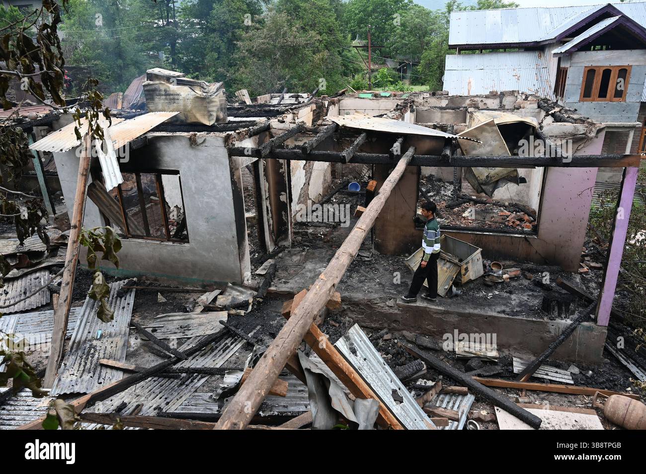 URI, INDIA - MAY 8: People walk outside a damaged houses after a ...