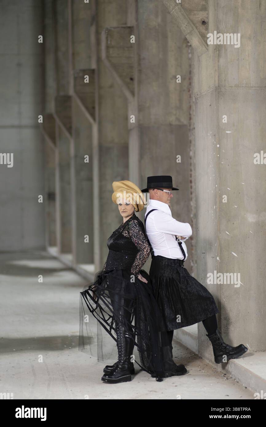 Fashionably dressed couple in industrial environment, standing against ...