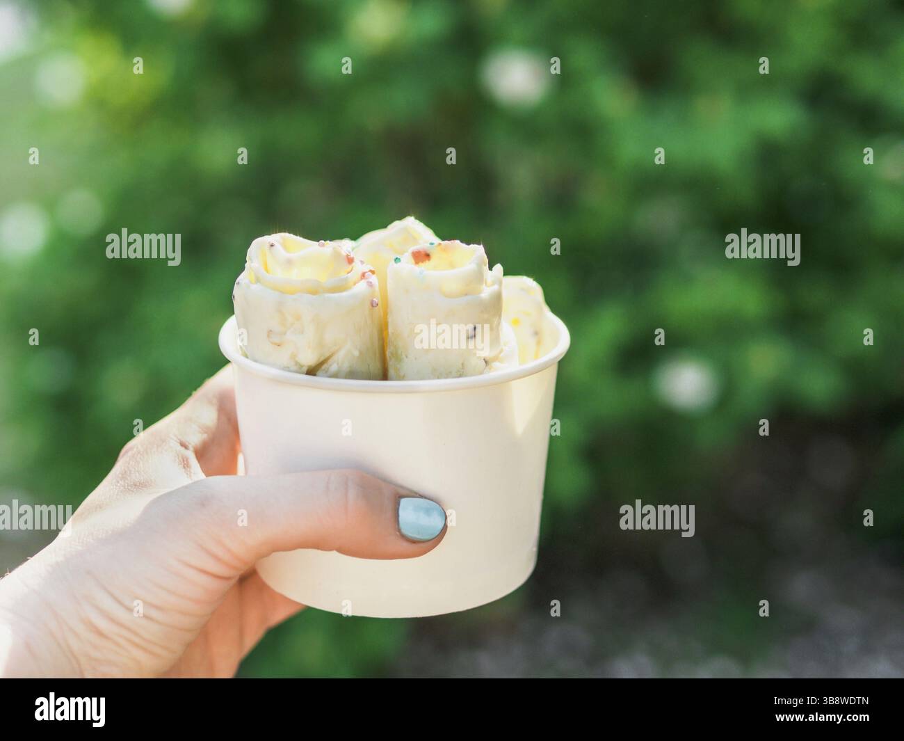 Rolled ice cream in cone cup in woman hand. Woman holds cone cup with ...