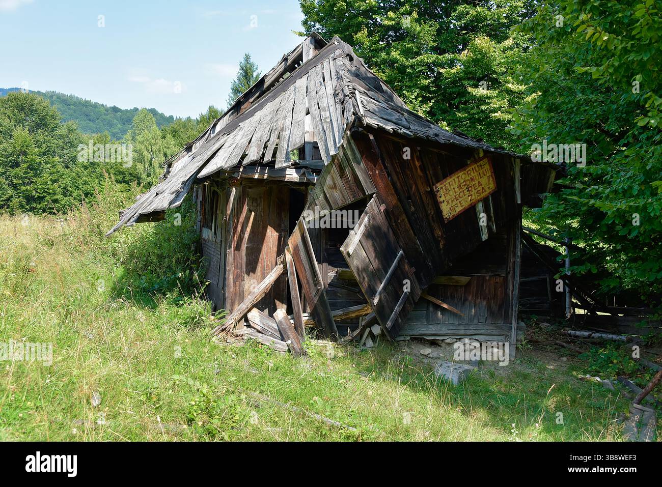 Old wooden cabin with severely collapsed roof and leaning walls on a ...
