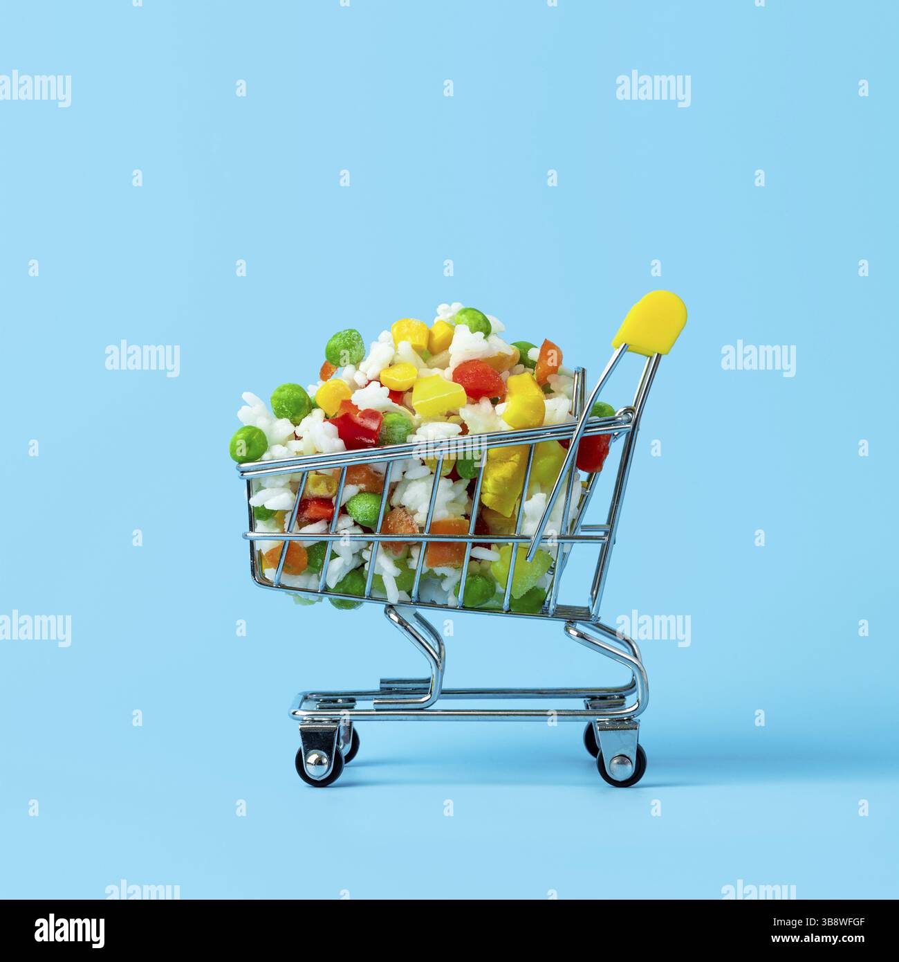 Frozen vegetables assorted in toy shopping cart on blue background ...
