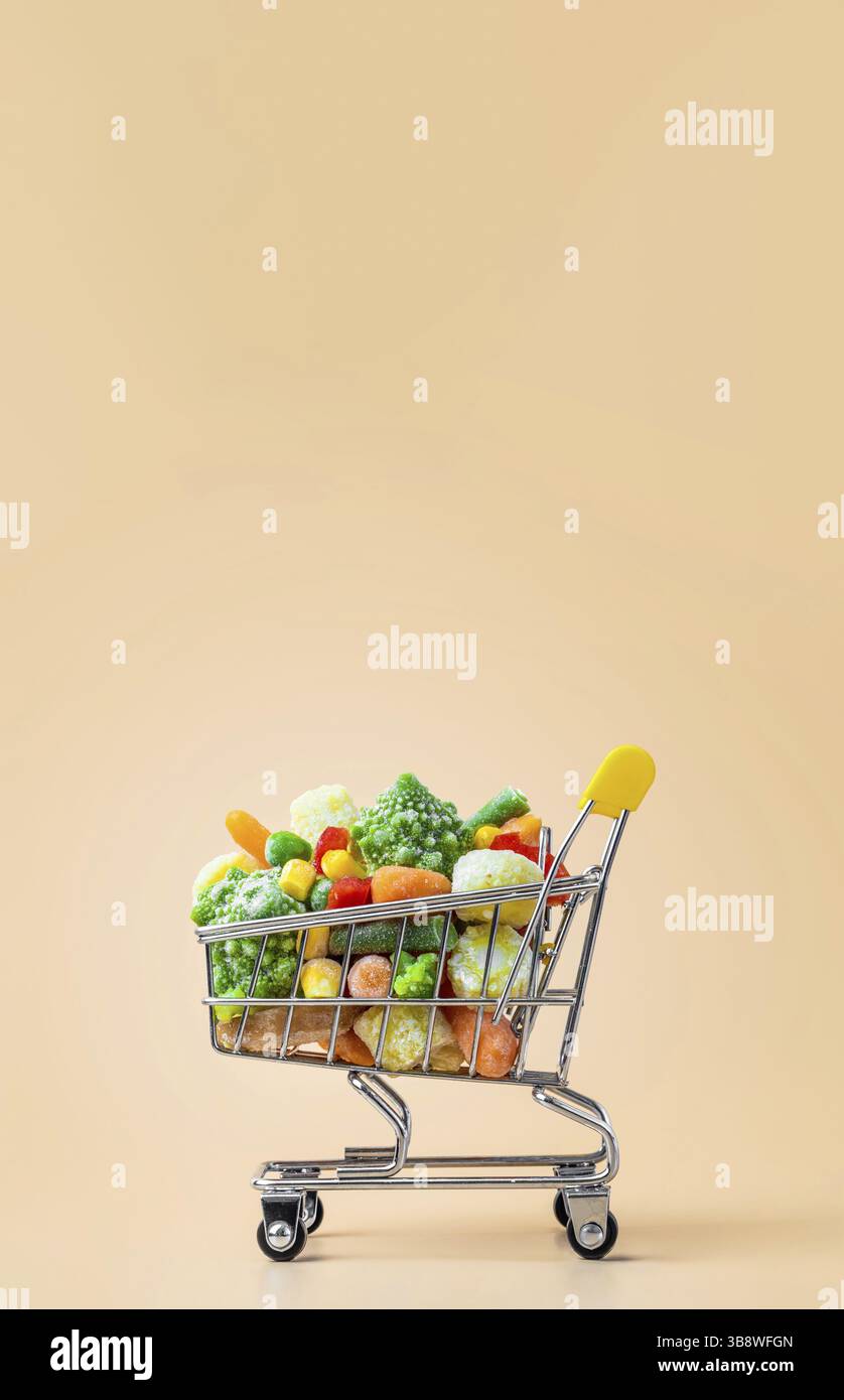 Frozen vegetables assorted in toy shopping cart on cream background ...