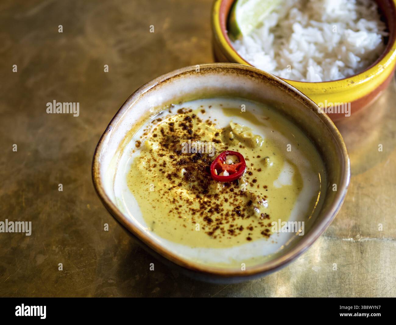 Yellow curry with cauliflower and chickpea and rice on metal tabletop ...