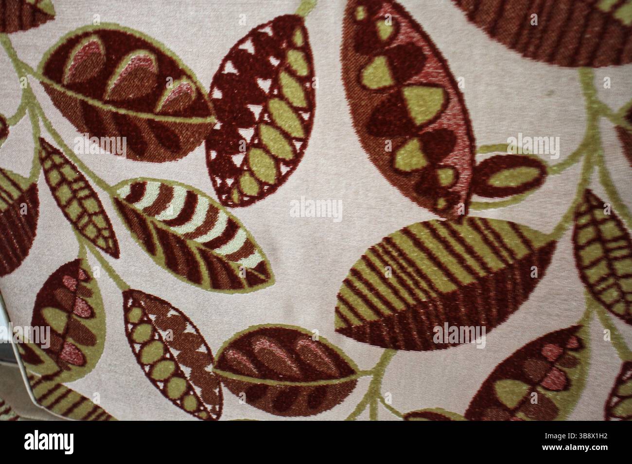 A fabric with a decorative leaf and branch pattern. The leaves are ...
