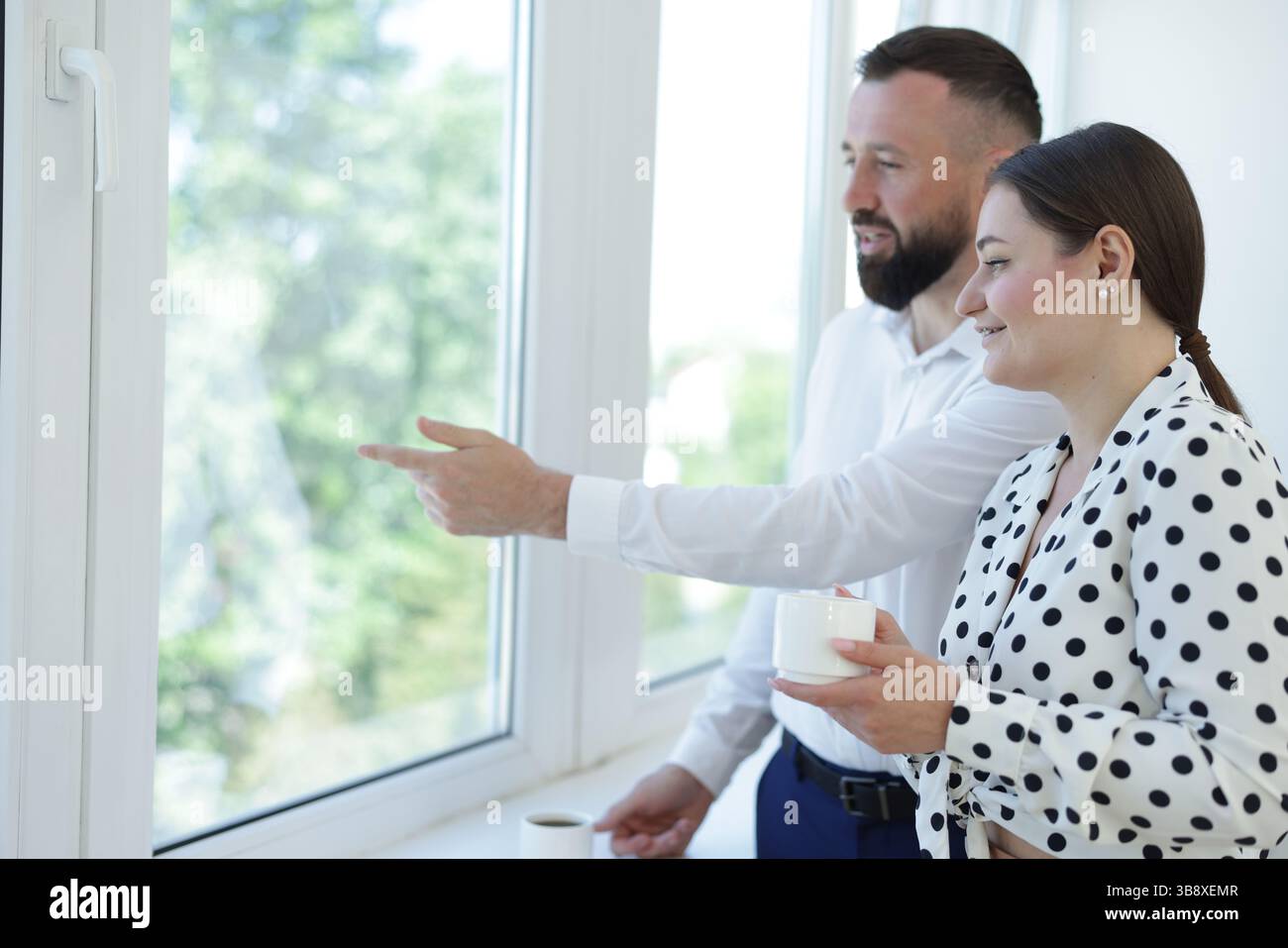 Colleagues looking out window during coffee break in office Stock Photo ...