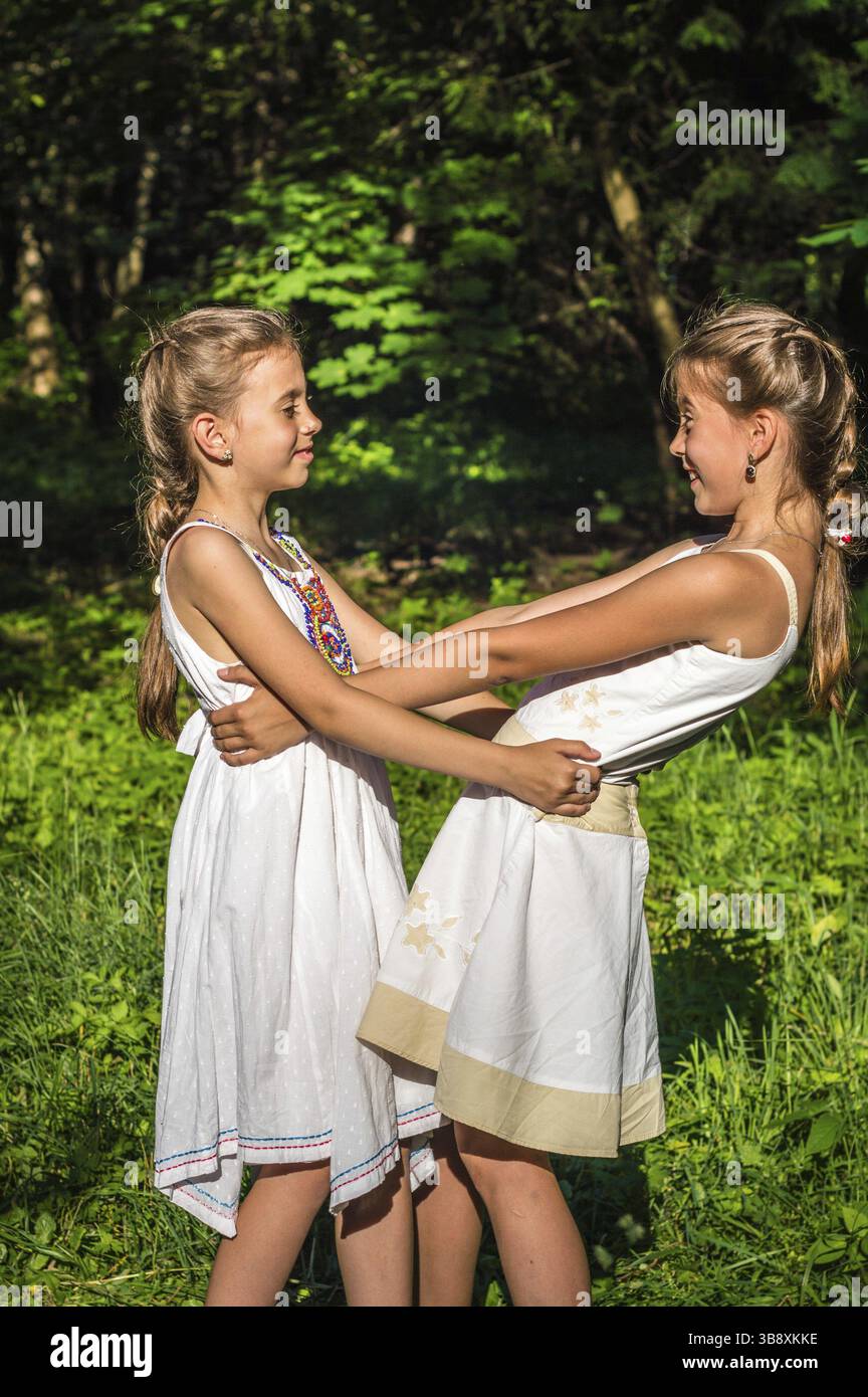 Two beautiful daughters hugging and dancing in the park Stock Photo - Alamy