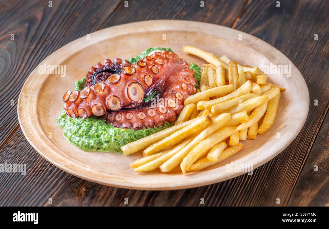 Roasted octopus tentacles served with creamy spinach and golden fries ...