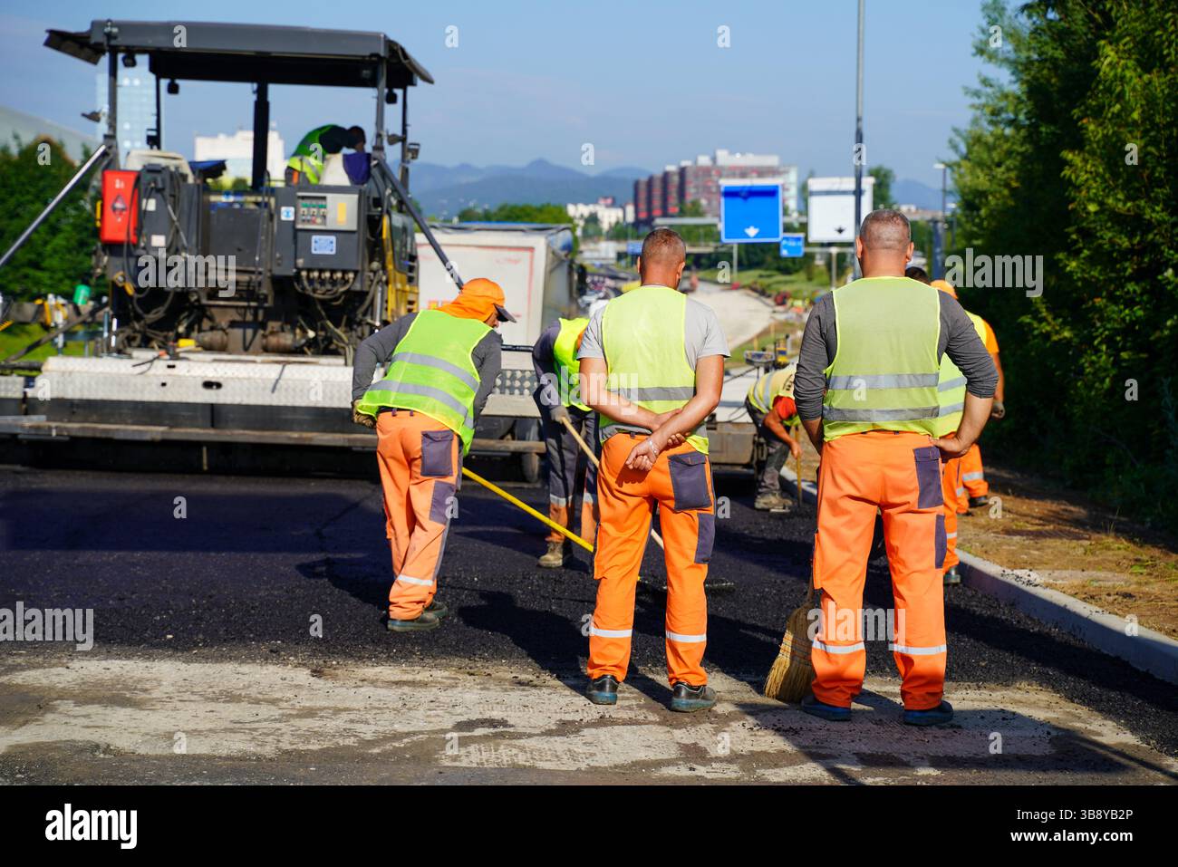 Construction Workers Spreading Asphalt by Hand Tools Behind Asphalt ...
