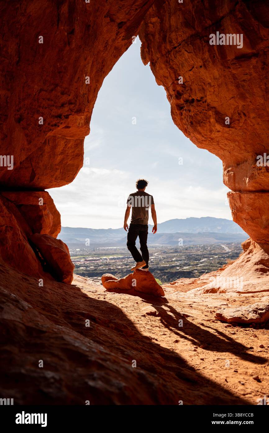 A man standing and looking out from Scout Cave over St. George, Utah. A ...