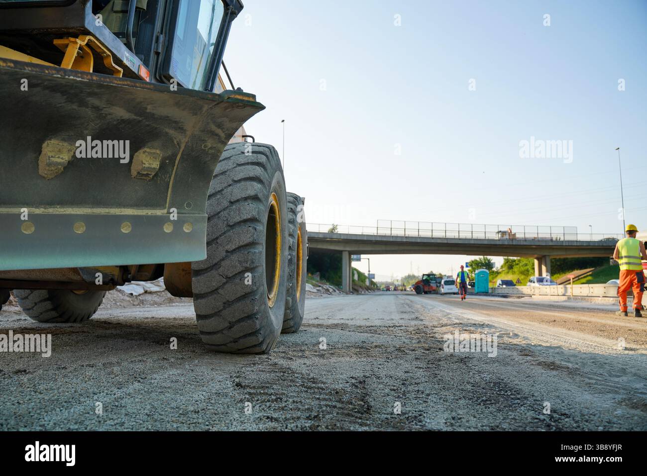 Motor grader operating on a highway construction site, smoothing and ...