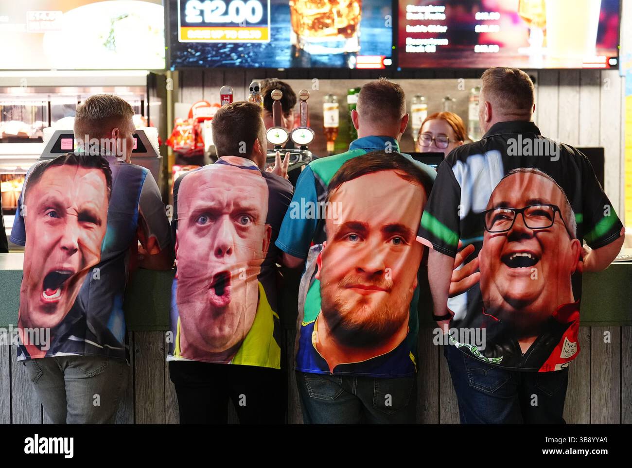 People wearing shirts adorned with the faces of darts players grab a ...