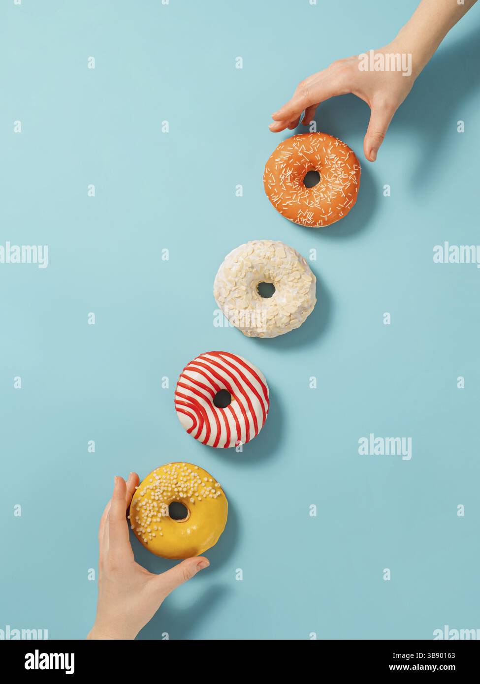 Two hands reach for donuts on blue background, top view. Creative ...