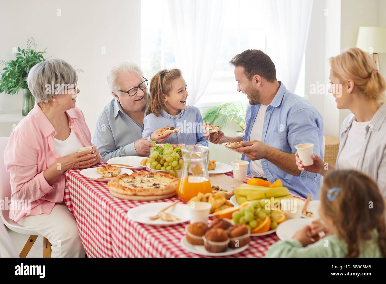 Happy big family gathering eating at table, laughing three generations ...