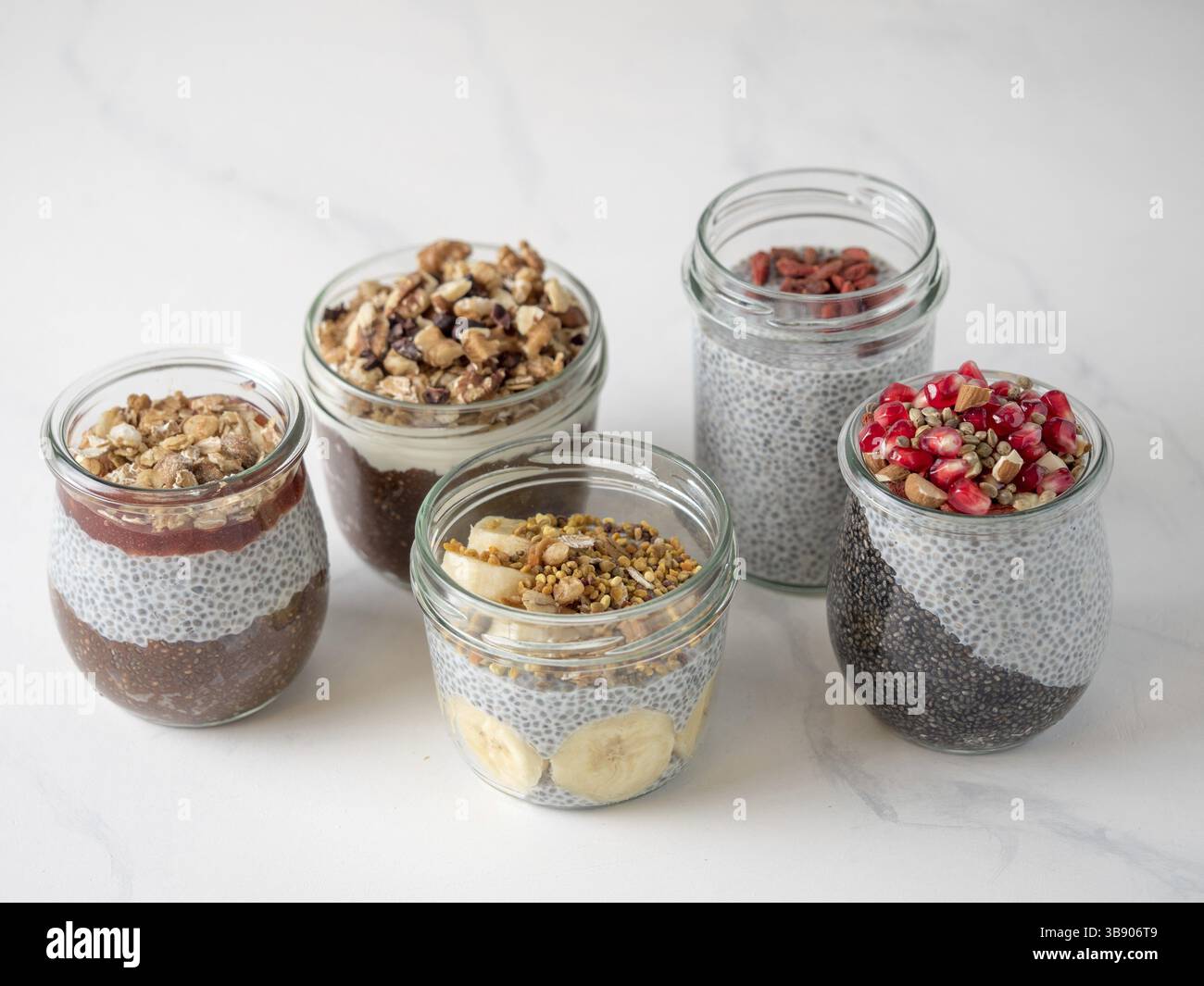 Set of chia pudding in different glass jars on white marble. Assortment ...