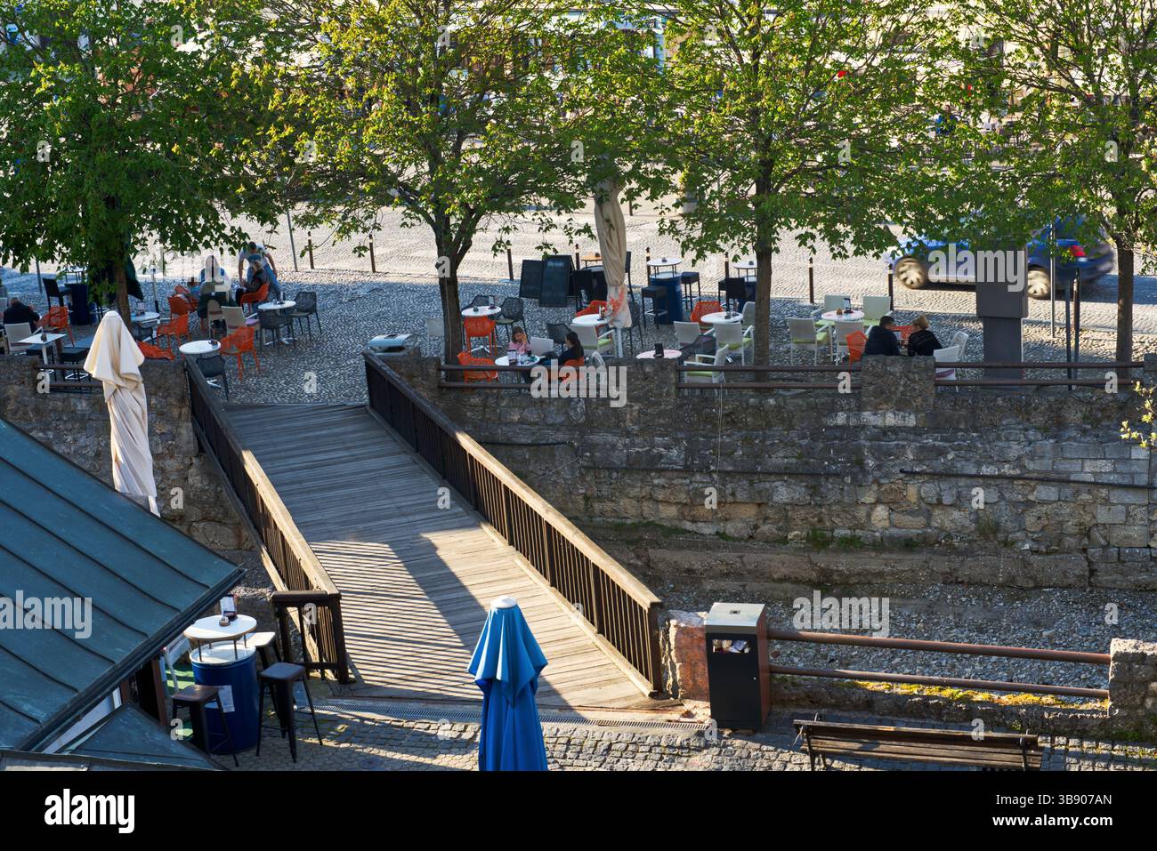 A view from above shows a wooden bridge leading to an outdoor cafe area ...