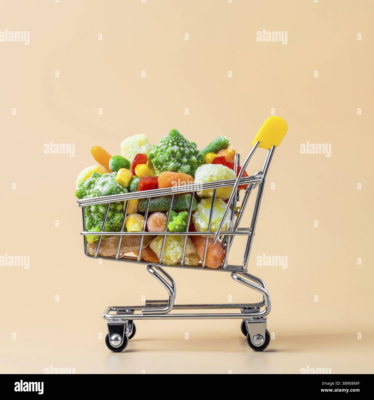 Frozen vegetables assorted in toy shopping cart on cream background ...