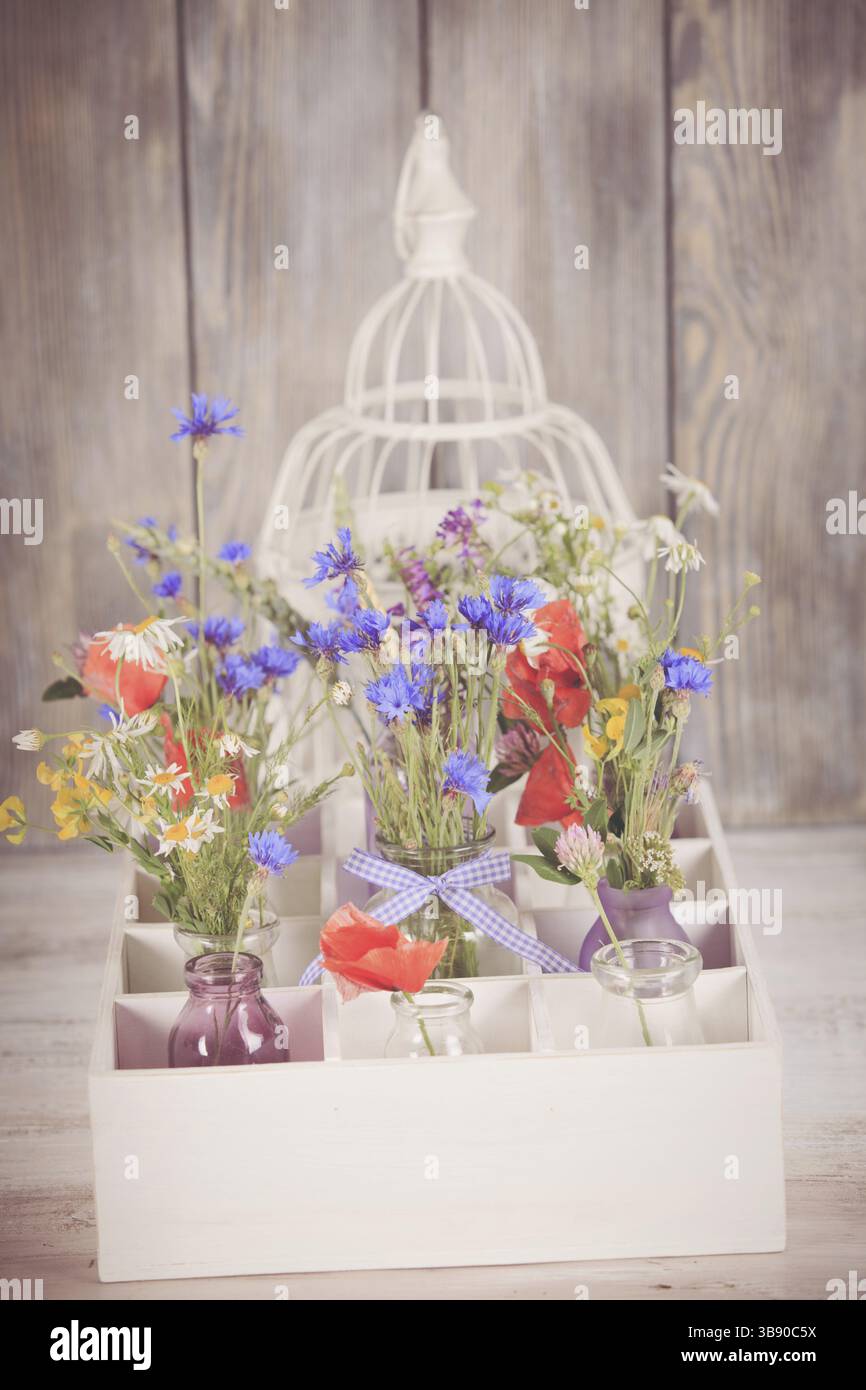 Wildflowers in bottles in the box. Kitchen flowers decor Stock Photo ...