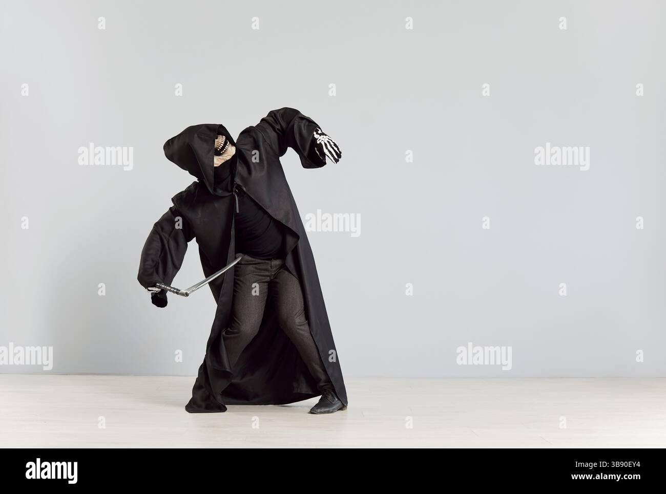 Man in grim reaper death costume having fun isolated on studio gray ...