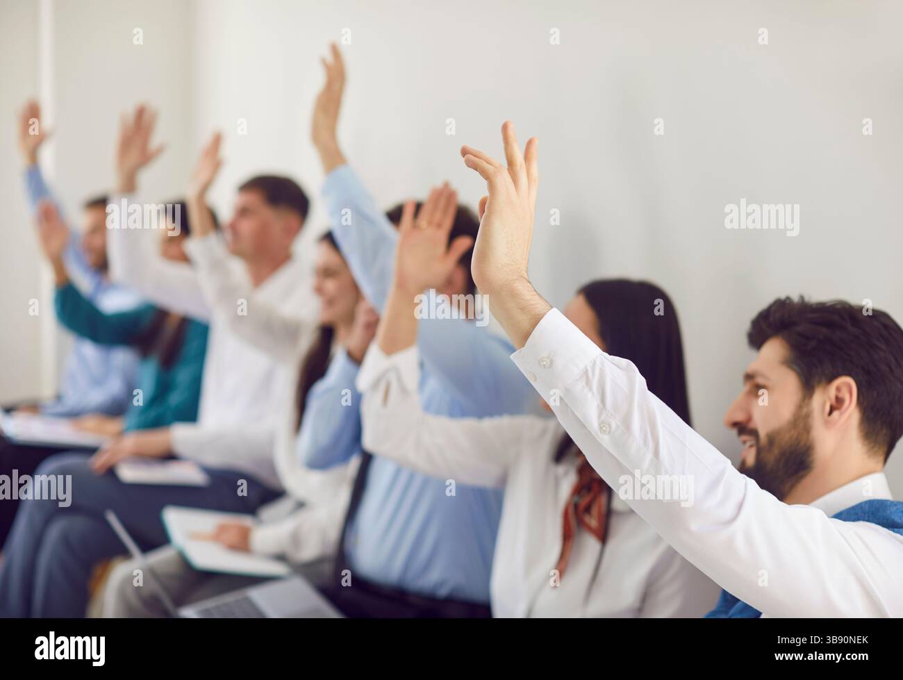 Young cheerful company employees raising hands to vote at the ...