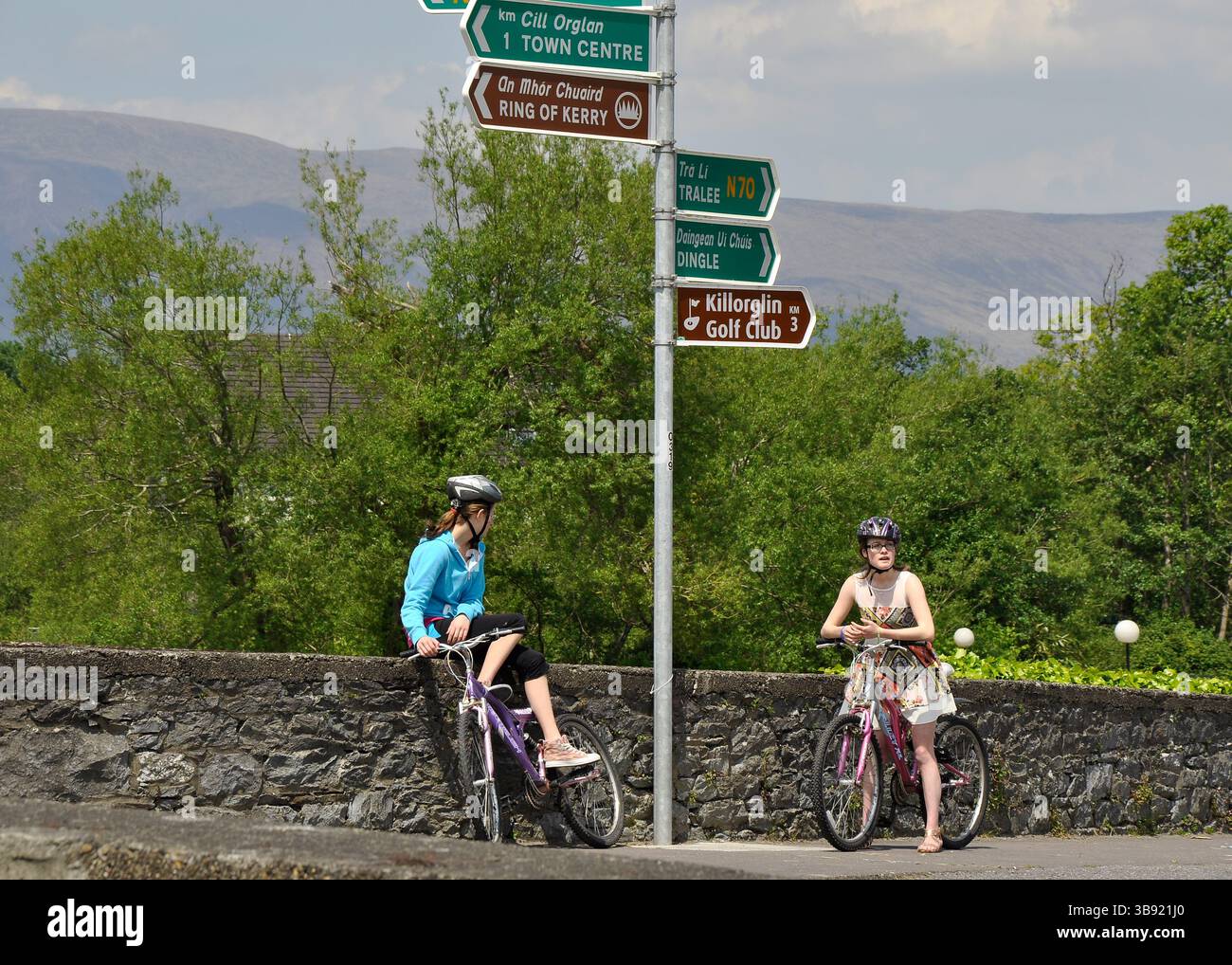 Two young female tourists with bicycles at rural crossroad and multiple ...