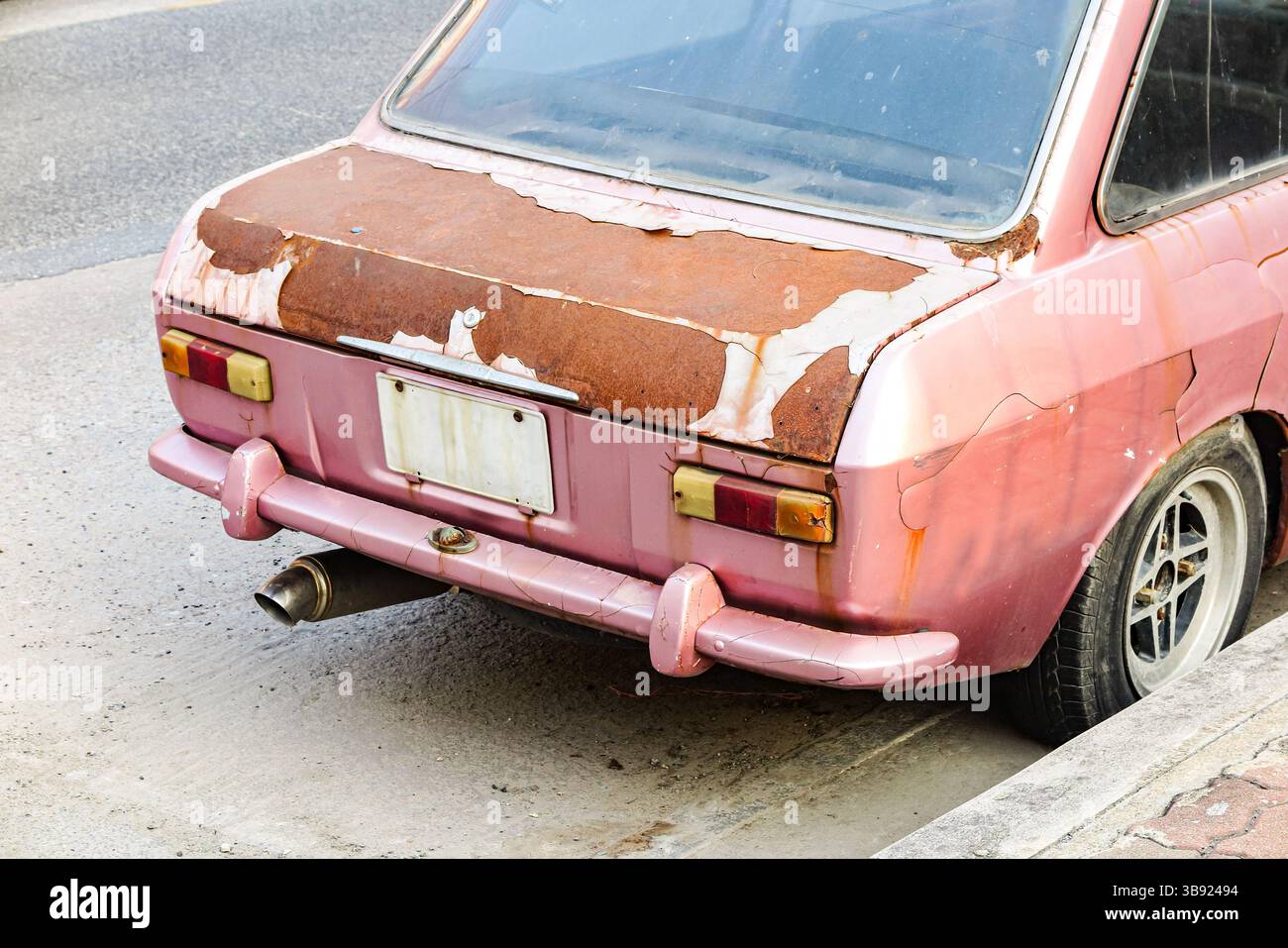 The rear of abandoned old rusty car on the side of the road Stock Photo ...