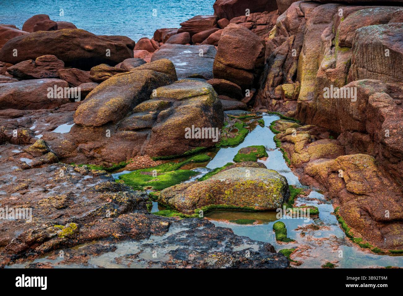 Rugged shoreline with red granite rock formations and turquoise sea ...