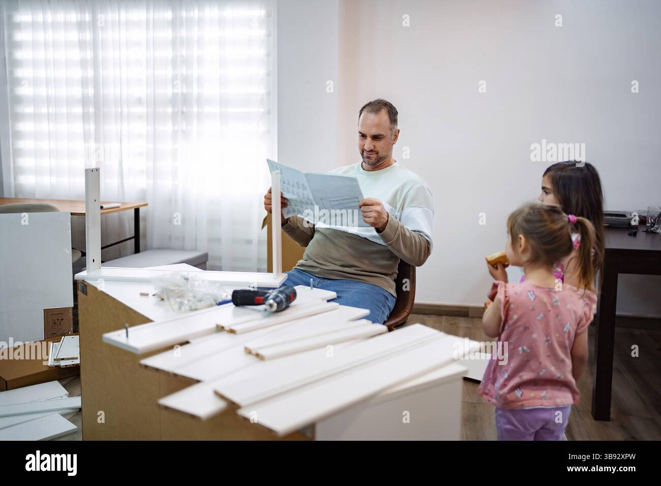 Father and daughters enjoy a DIY project at home on a weekend Stock ...