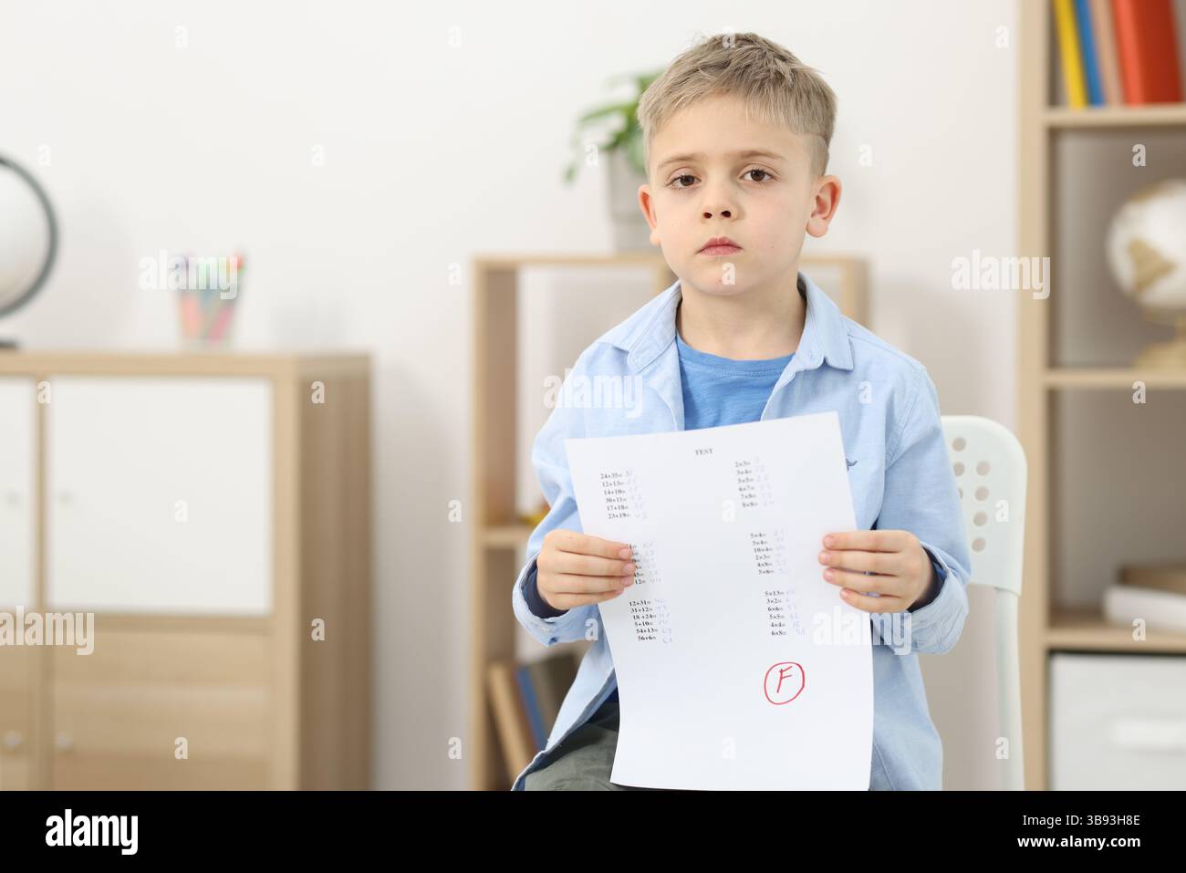 School grade. Sad boy holding answer sheet with letter F indoors, space ...
