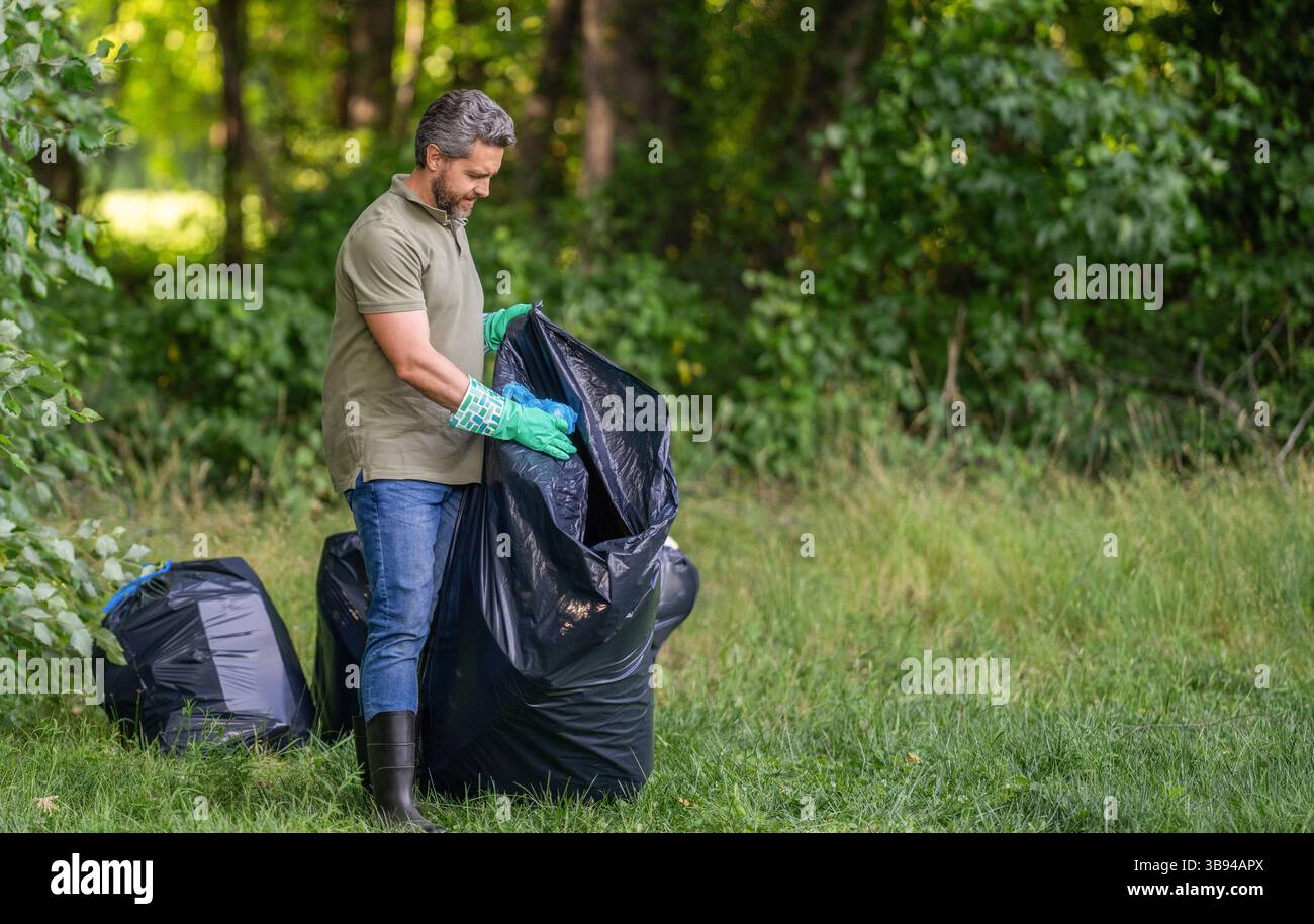 Man in rubber gloves with trash bag clean up garbage. Man collecting ...