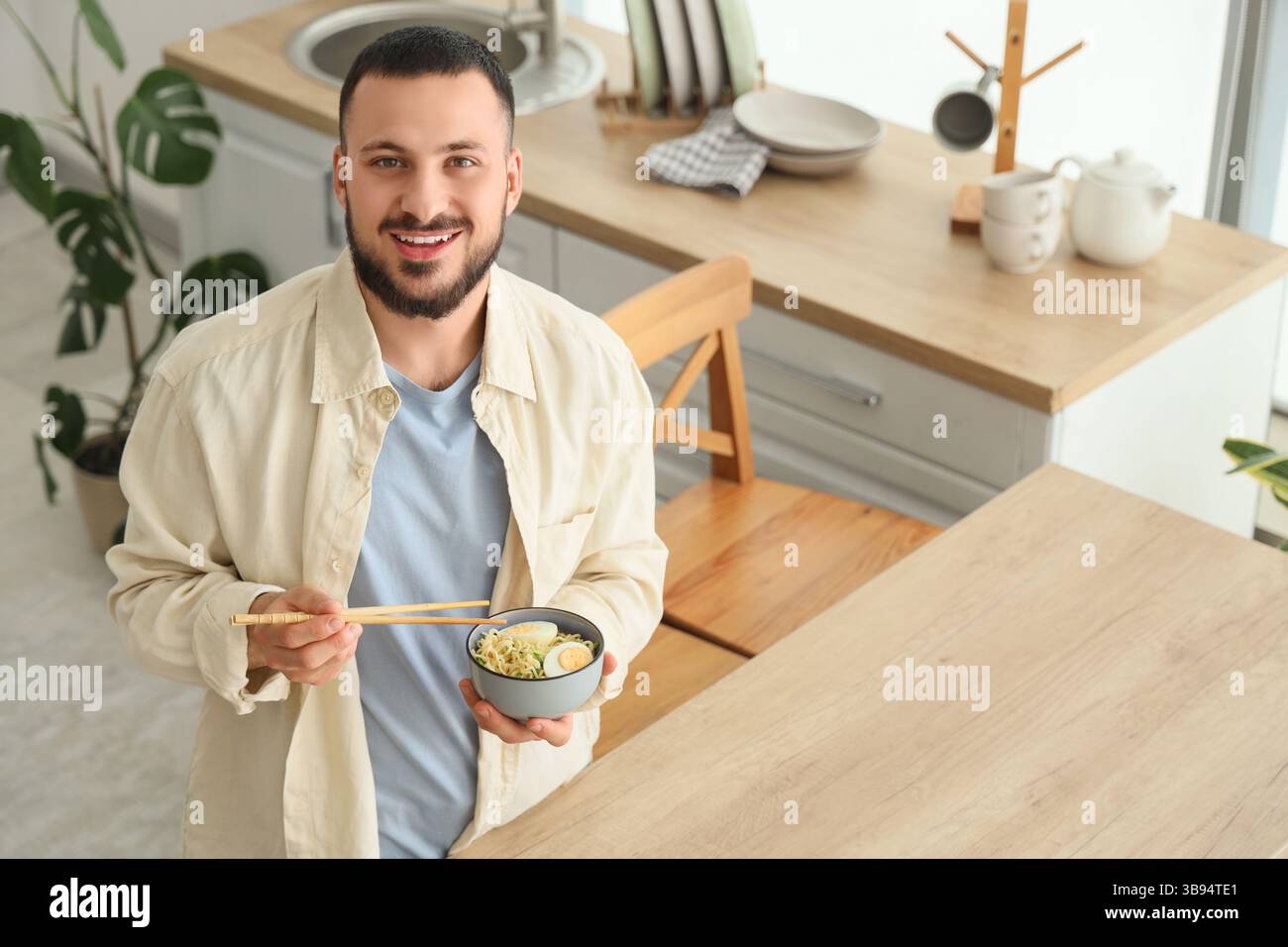 Young man eating tasty ramen in kitchen Stock Photo - Alamy