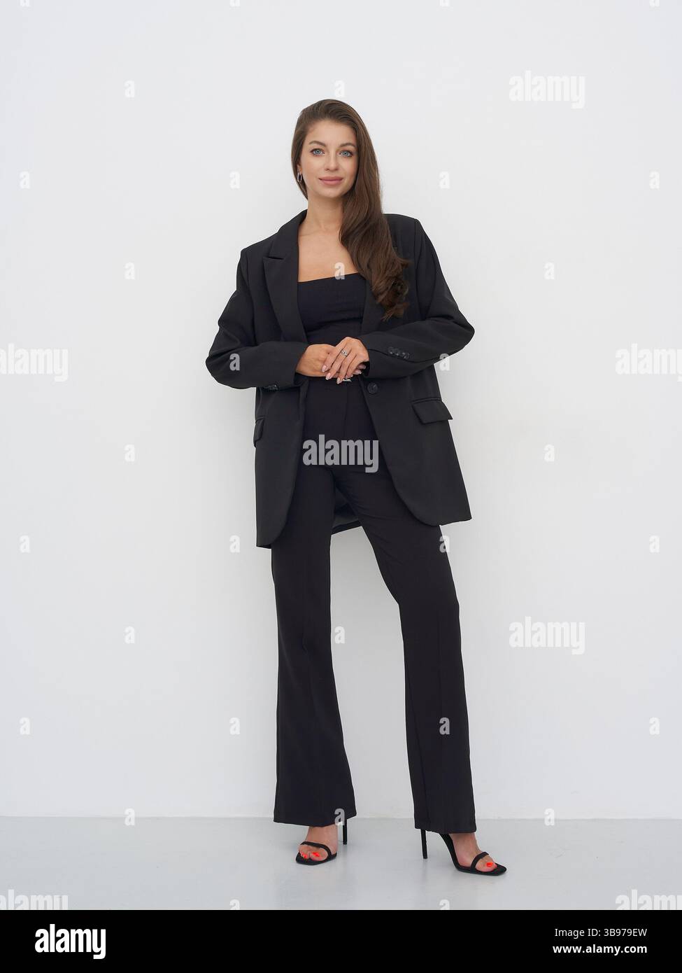 Confident female model poses in stylish black outfit against a clean ...