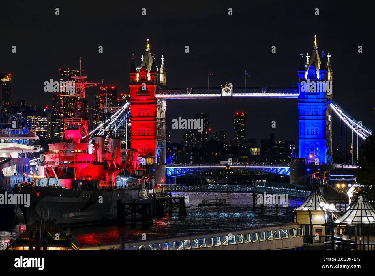 London, UK. 8th May, 2025. Tower Bridge is lit up in red, white, and ...